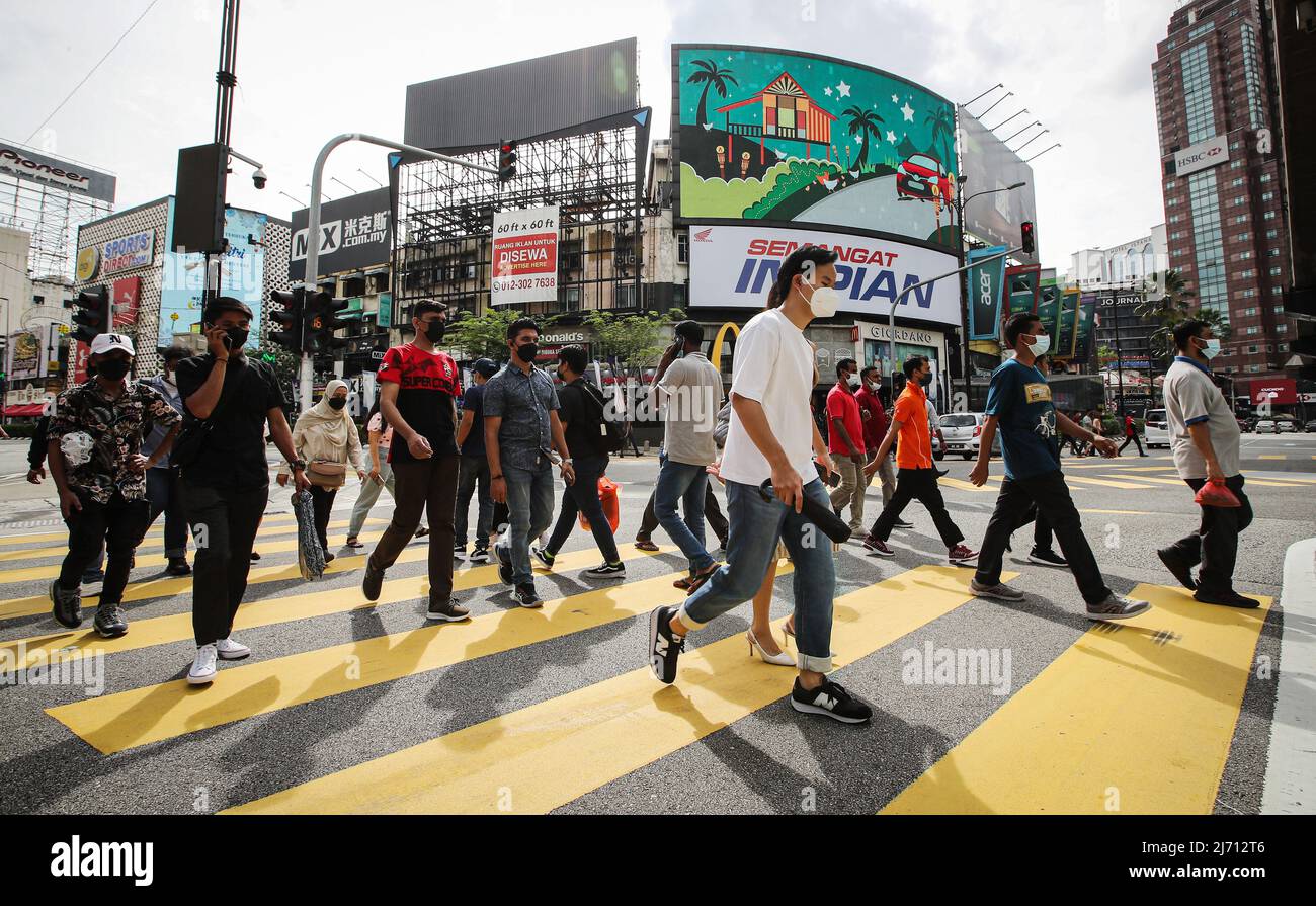 Pedestrians wearing face masks are seen crossing the street near a ...