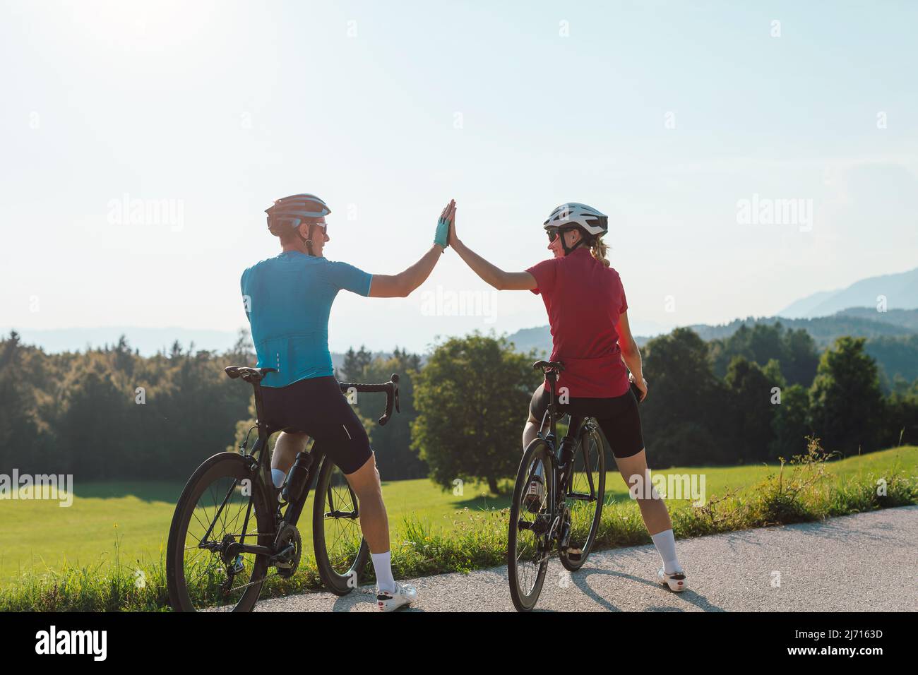 Road cyclists couple taking a ride break along a scenic cycling route ...