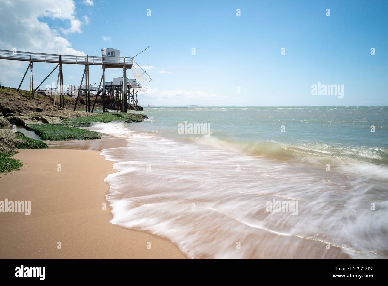 Fishing huts on Atlantic coast with ocean waves on sandy beach in ...