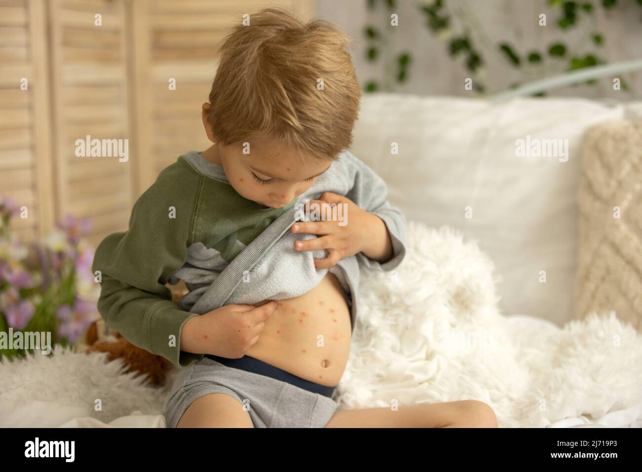 Toddler boy with chicken pox,lying in bed with fever, mother checking ...