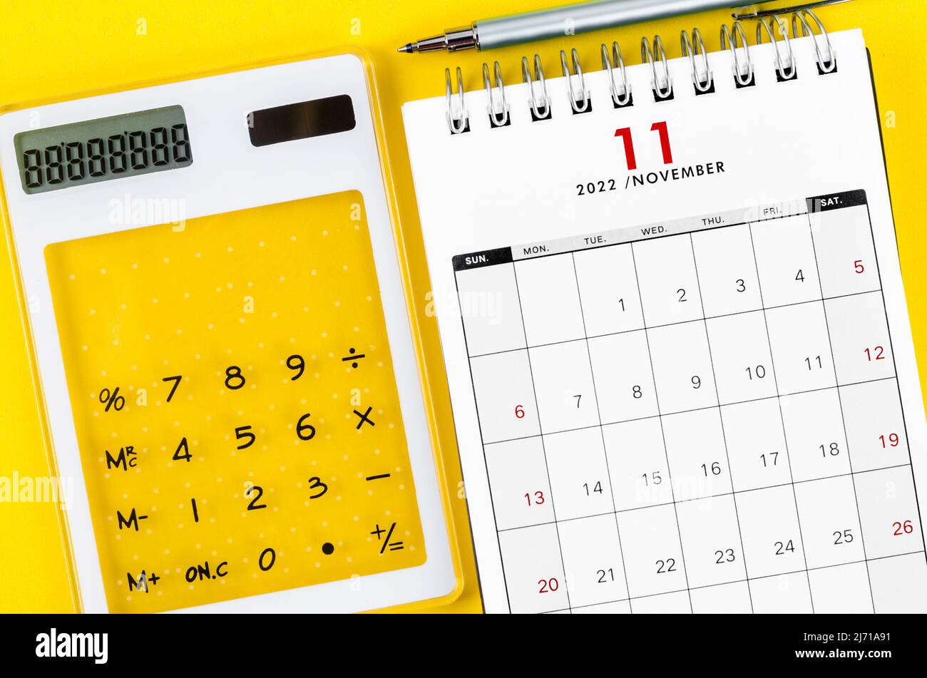 The November 2022 desk calendar with calculator and pen on yellow ...