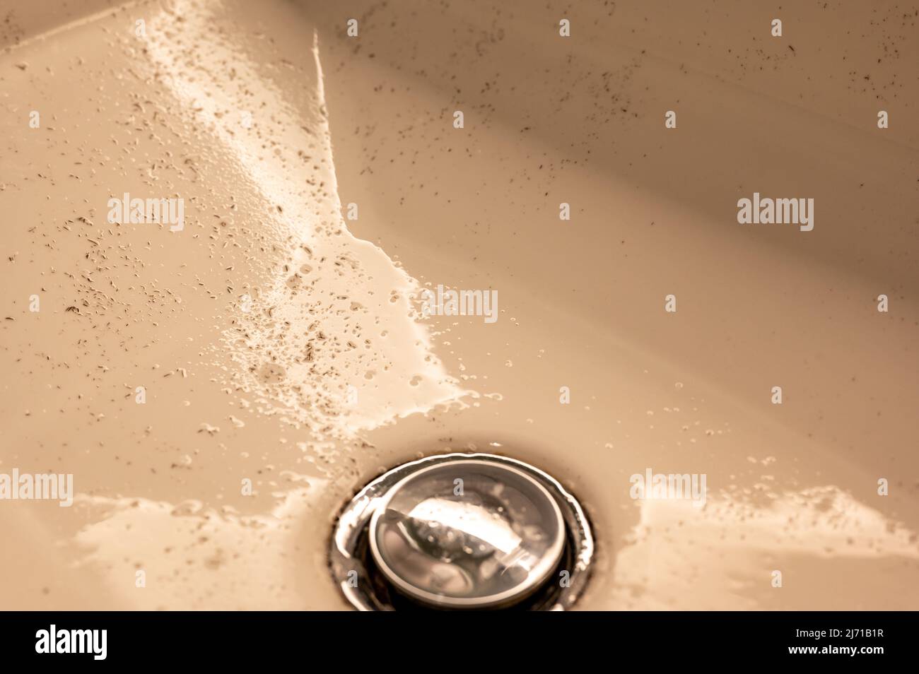Small pieces of hair left in a bathroom sink after a man finished ...
