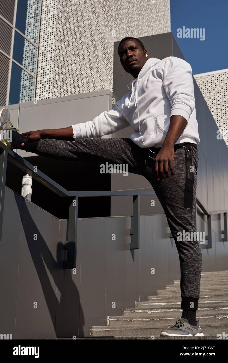 Low angle view of determined Black male athlete in sportswear doing ...