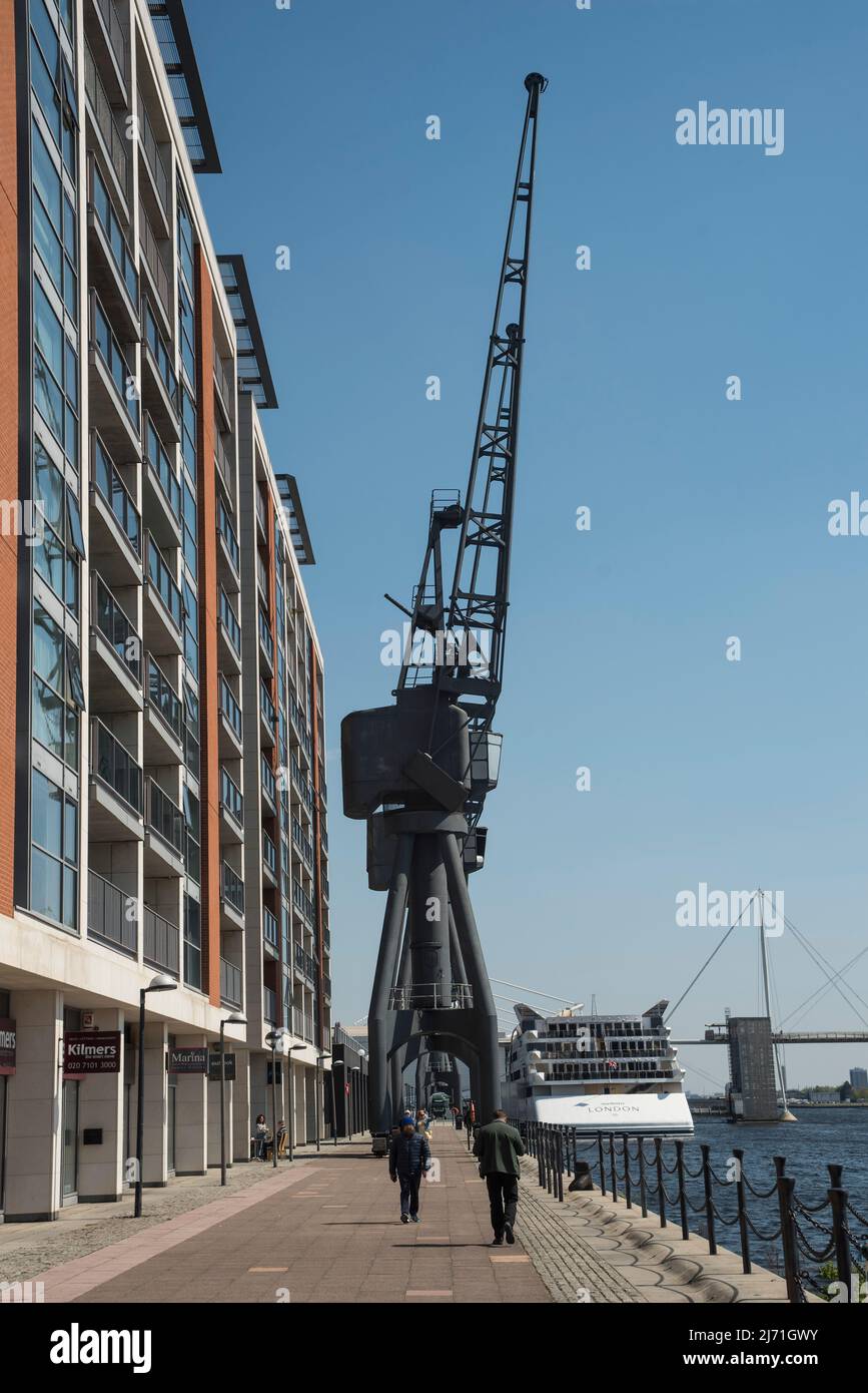 A line of old dock cranes in front of new apartment buildings in a dock ...
