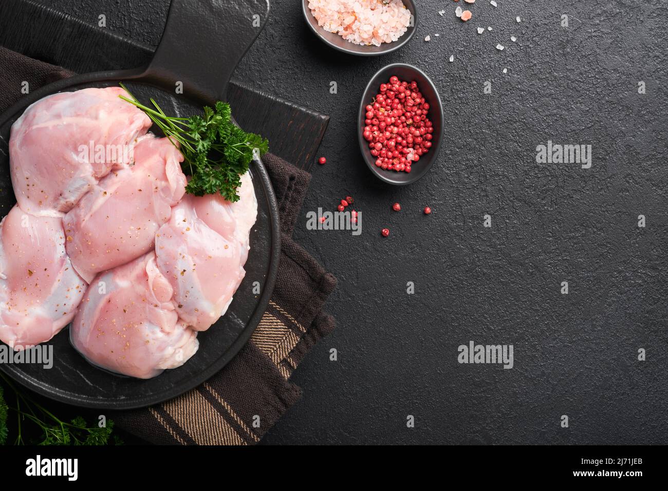 Raw chicken thigh fillet without skin with herbs and spices on black ...