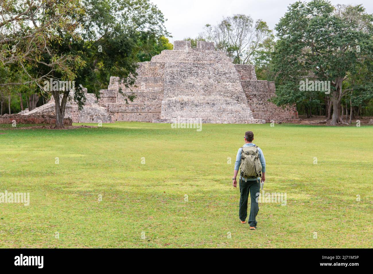 Tourist caucasian man with a backpack exploring mayan ruins of Edzna ...