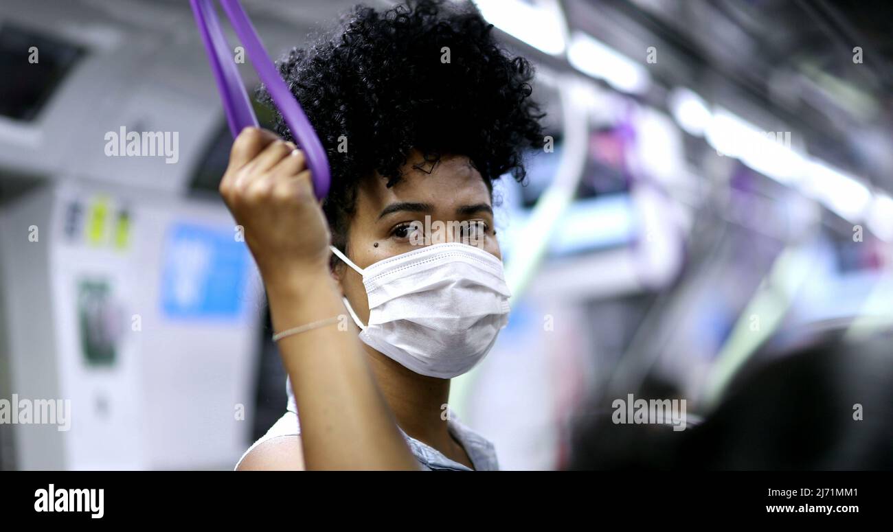 African american woman holding subway handrail during pandemic wearing ...