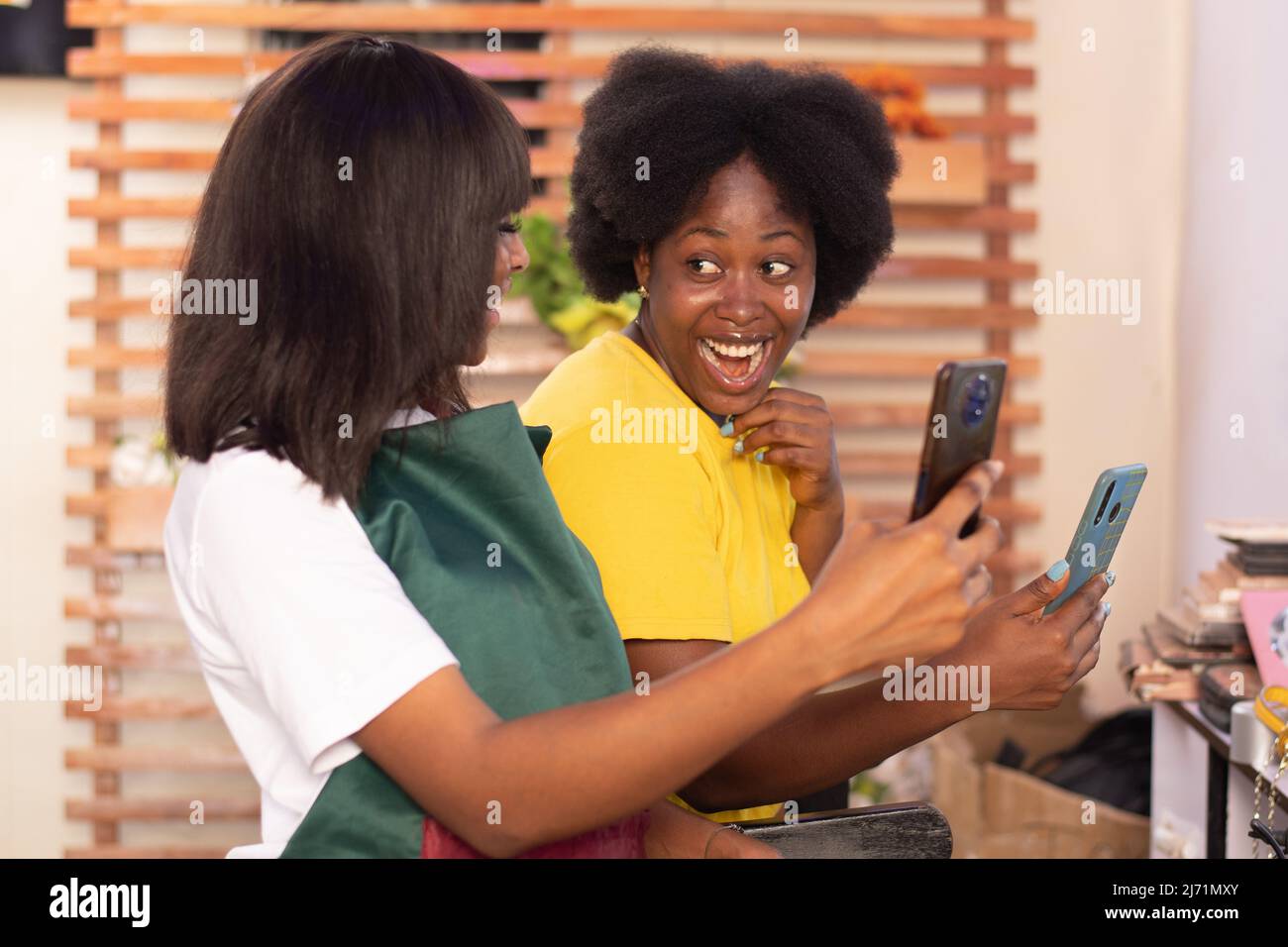 african women in a salon laughing while holding their phones Stock ...