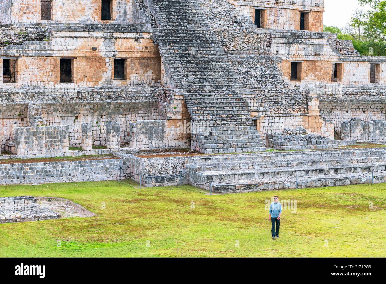 Tourist man visiting mayan ruins of Temple of the Five Storeys, Edzna ...