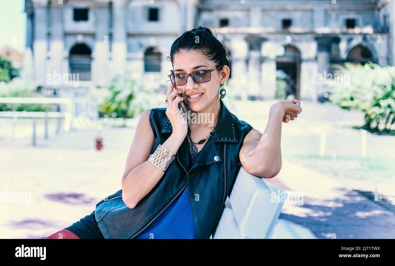 Urban style girl sitting on a bench calling on the phone, An attractive ...