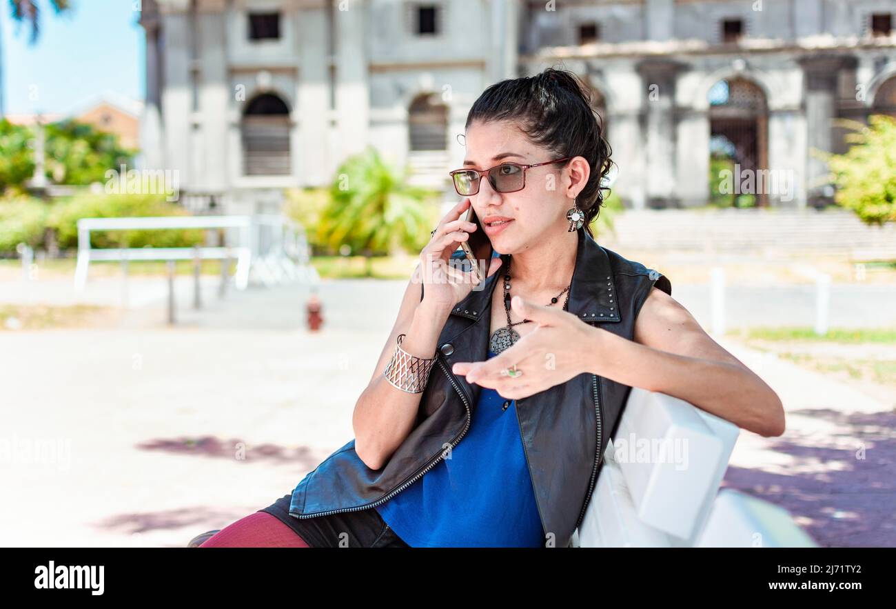 Urban style girl sitting on a bench calling on the phone, An attractive ...