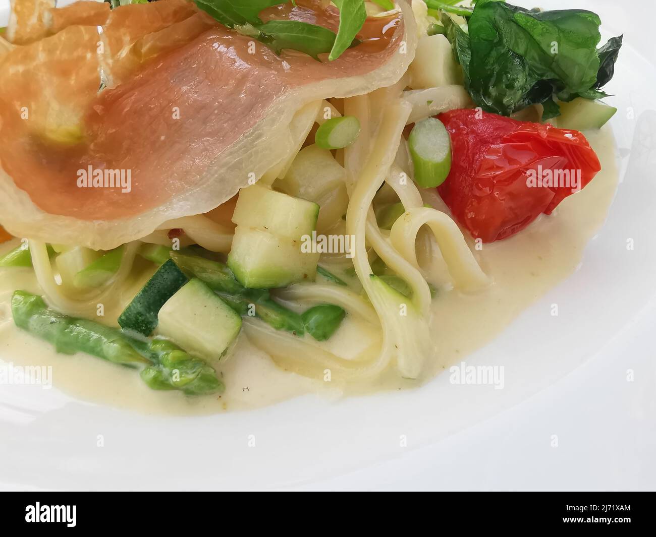 Gourmet pasta dish with parma ham, cheese sauce and vegetables Stock ...
