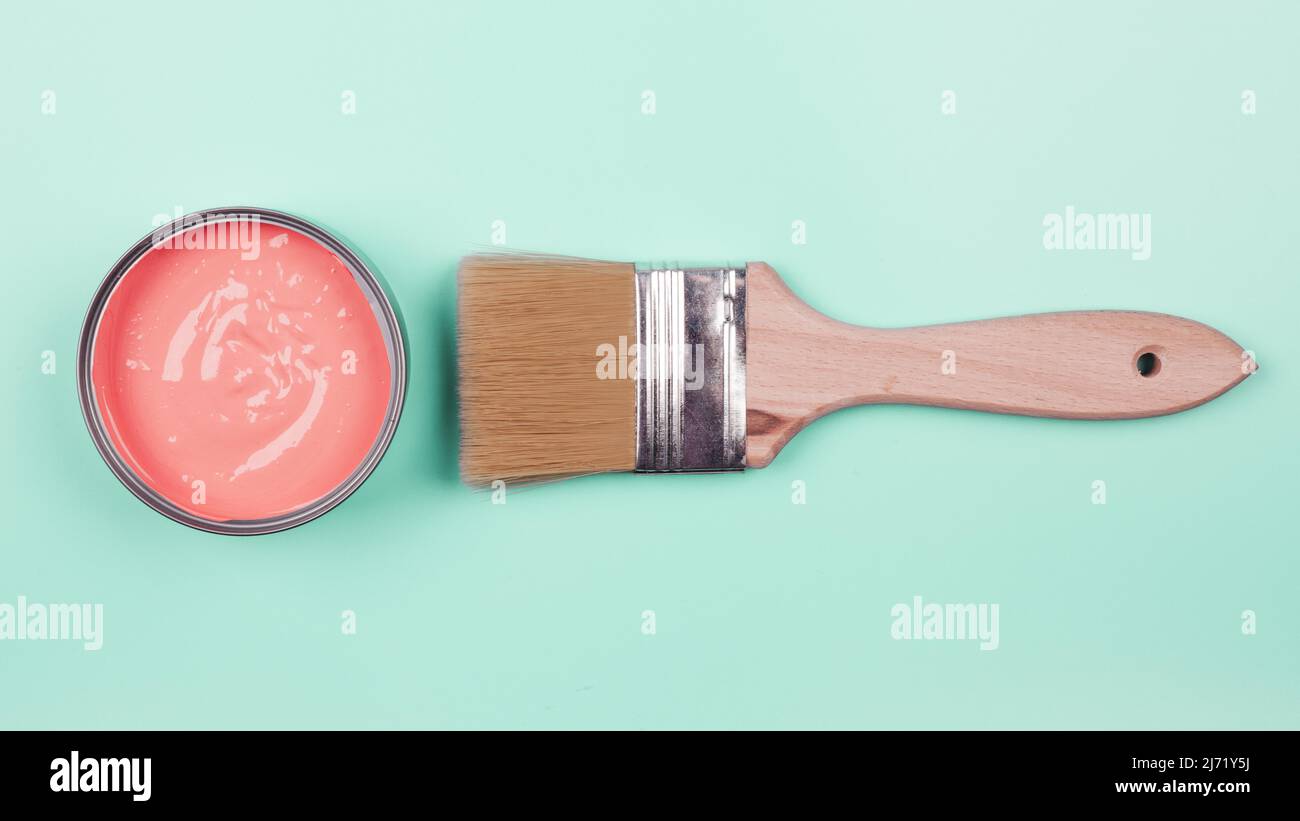 An elevated view of coral paint bucket and paintbrush on mint ...
