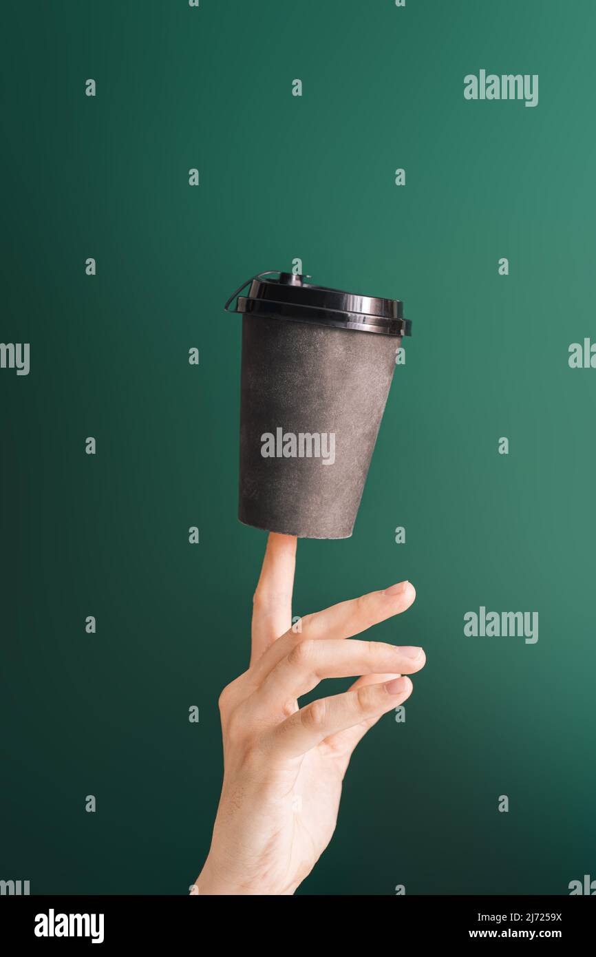 Dark cup on the index finger against green background Stock Photo - Alamy