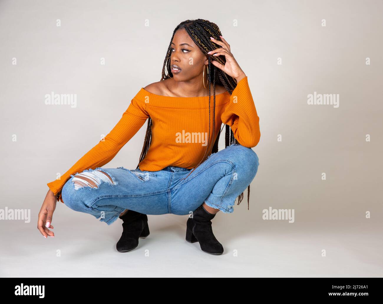 Studio shot of a young Black woman with vintage orange top and baggy ...