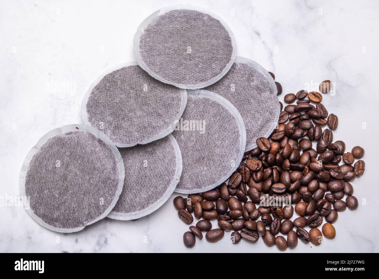 Top view of coffee pads and coffee beans on a marble surface as an ...