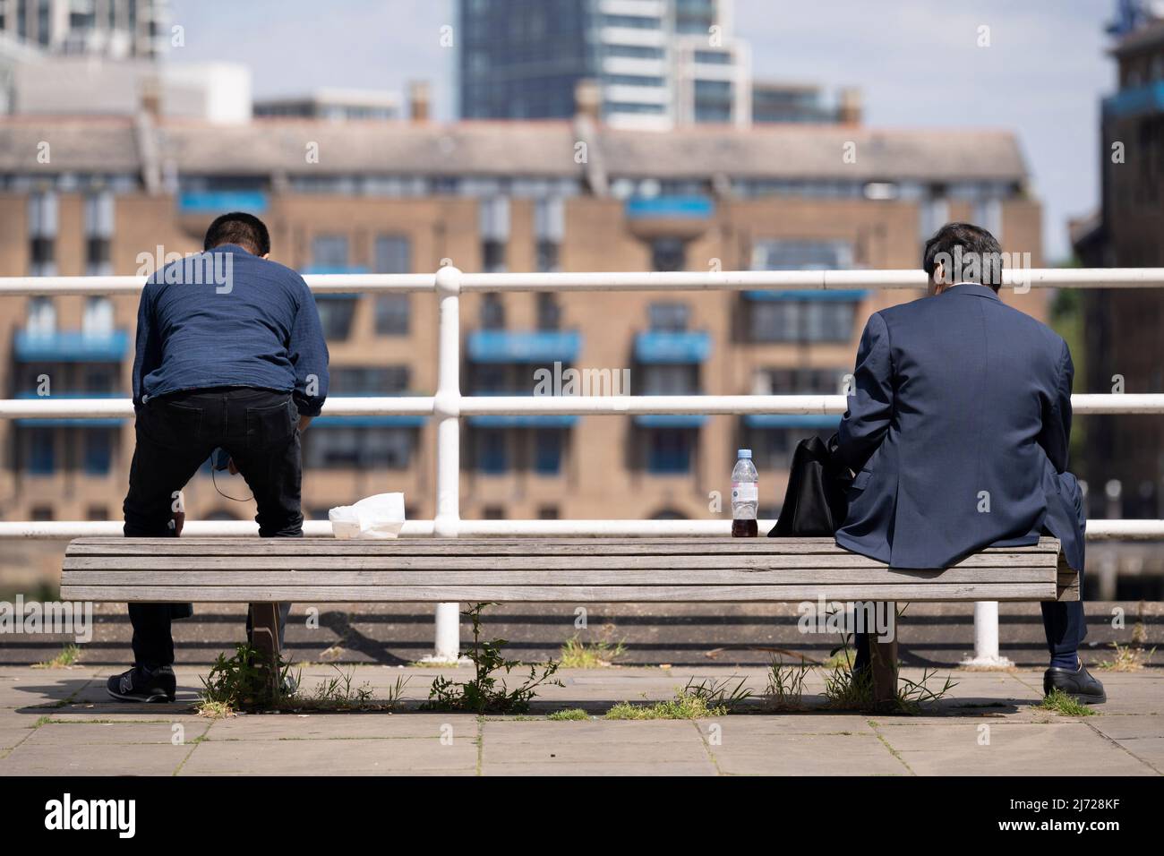 Two men occupy a riverside bench, one standing up to leave at Butler's ...