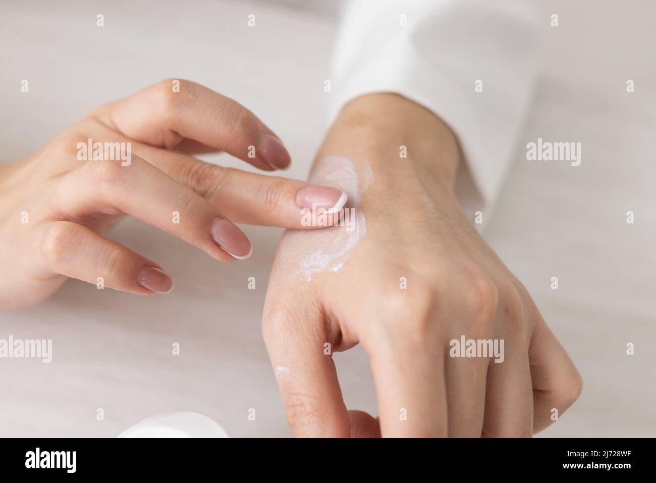 Female hands with cream. Woman applies cream on her hands. Palms down ...