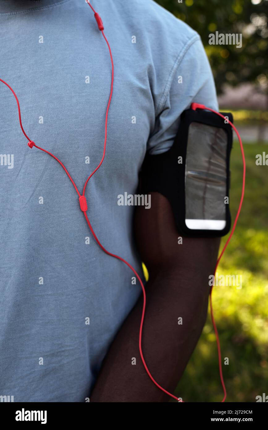 Runner with gadget. Unrecognizable athletic Black man standing outdoors ...