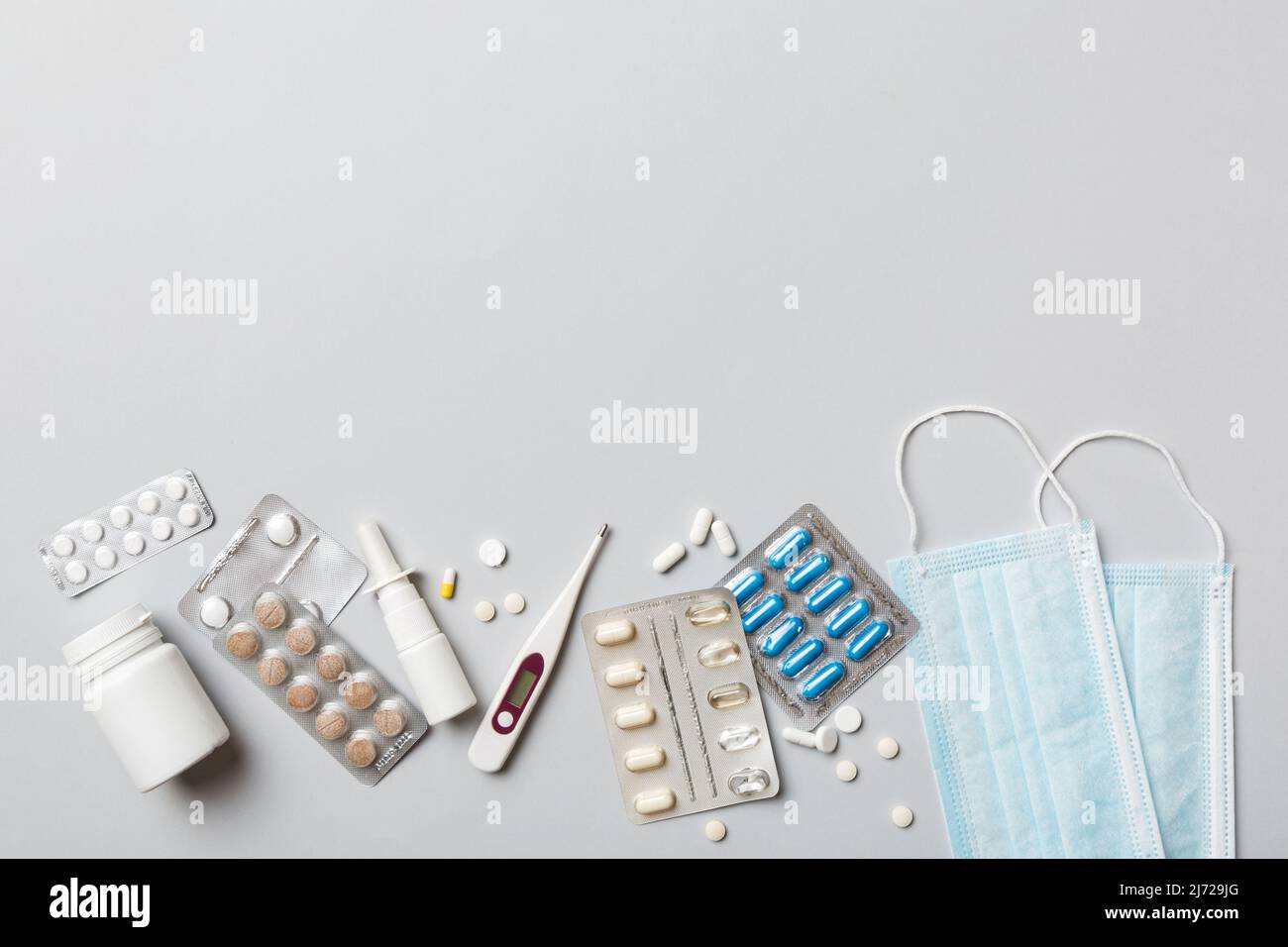 Protective face masks or surgical masks, medicine pills and thermometer ...