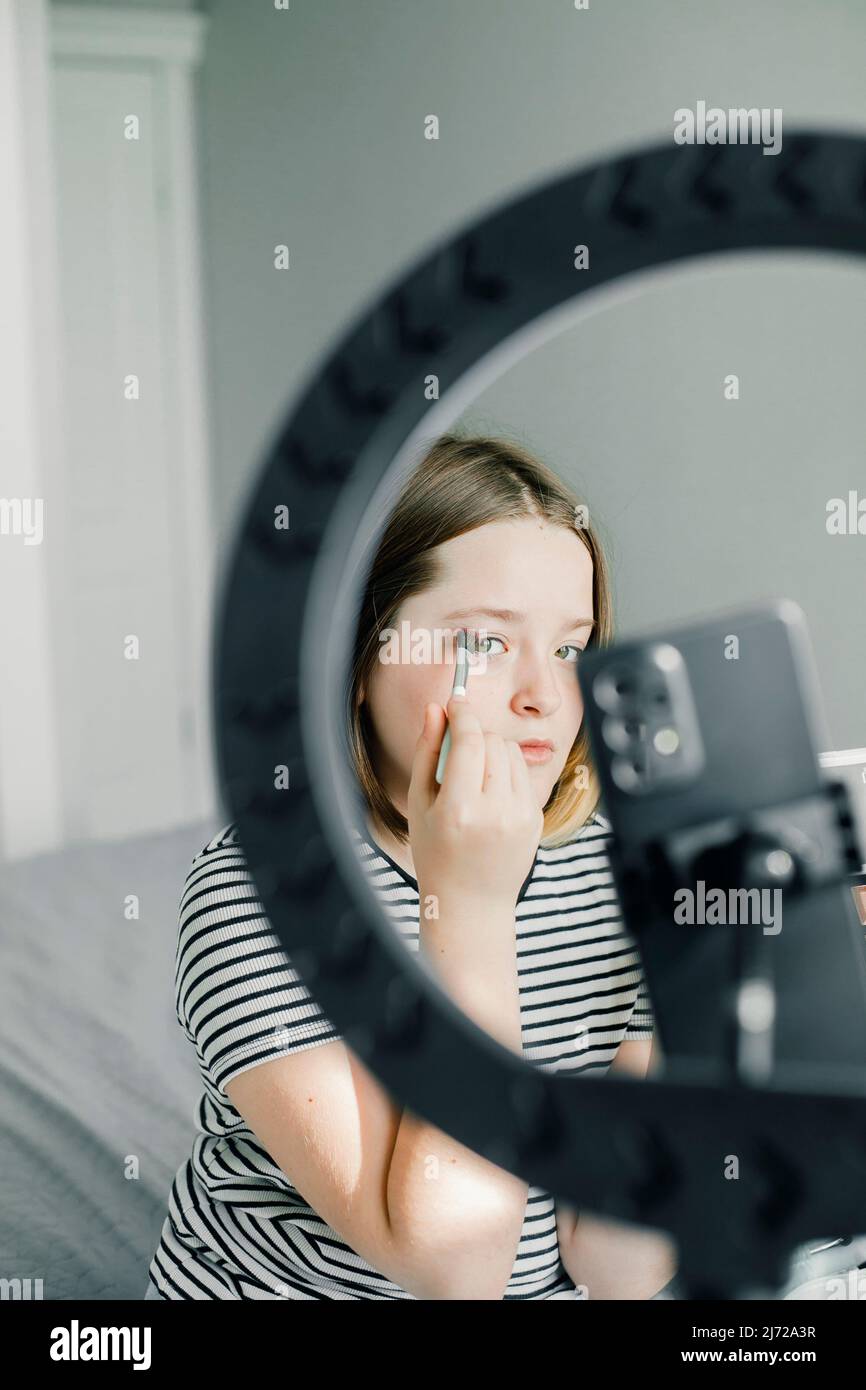 Teen girl beauty blogger with eyeshadows, brush and camera recording ...