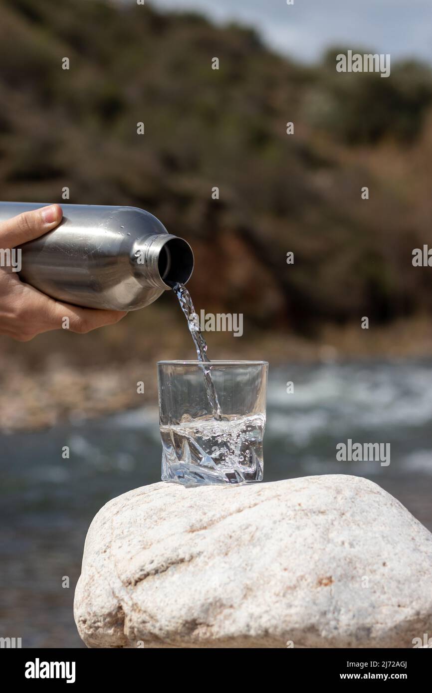 Close up pouring purified fresh drink water from the bottle on glass ...