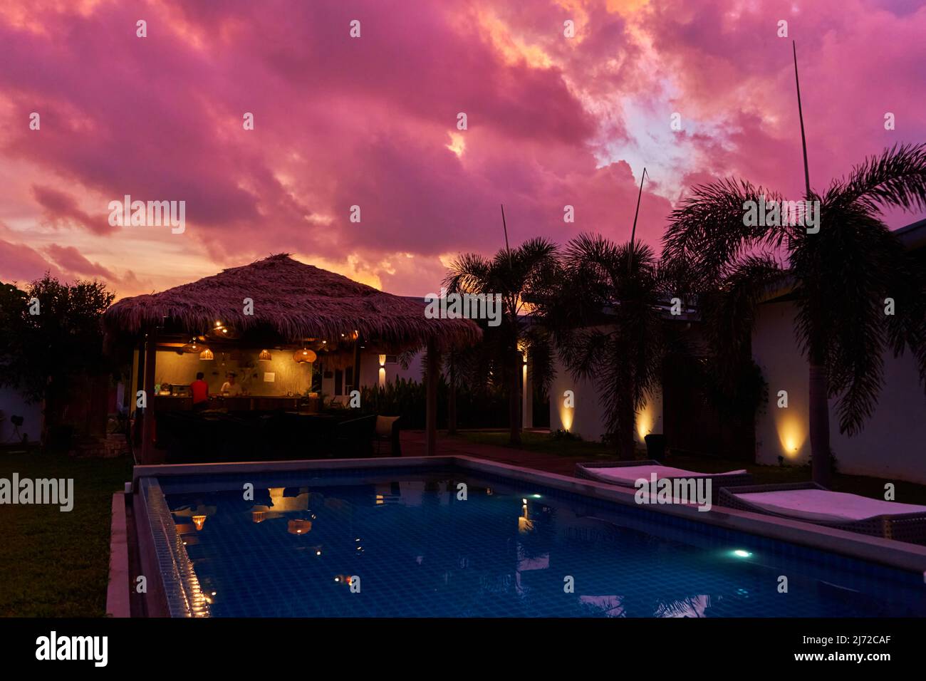 A gentle sunset sky over a thatched bungalow. An exotic resort in the ...