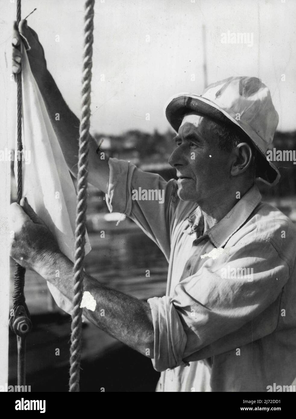 Eric Massey, skipper of Wanderer, affixes a white identification flag ...
