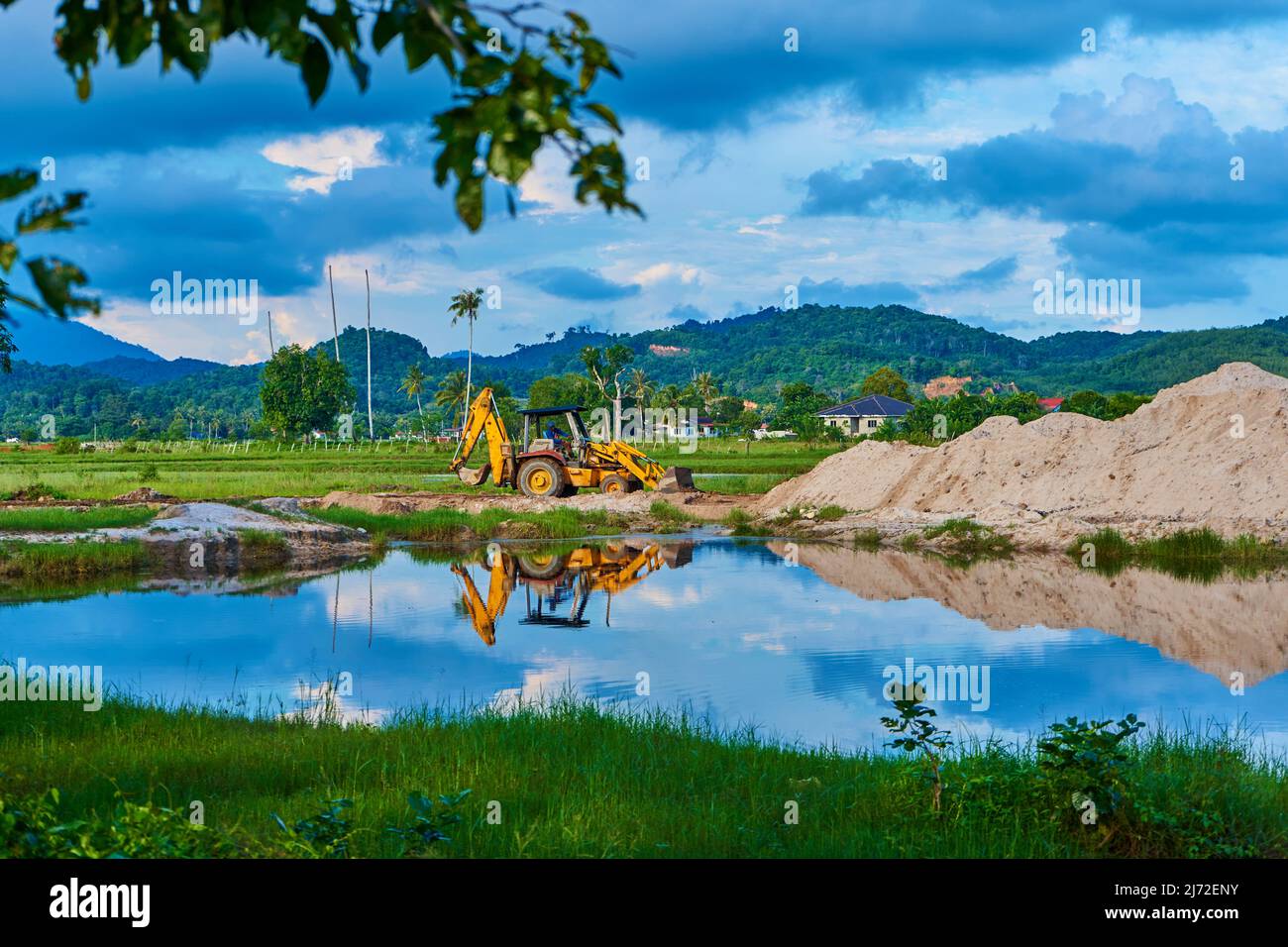 A construction tractor works in a field on a tropical island. Start of ...