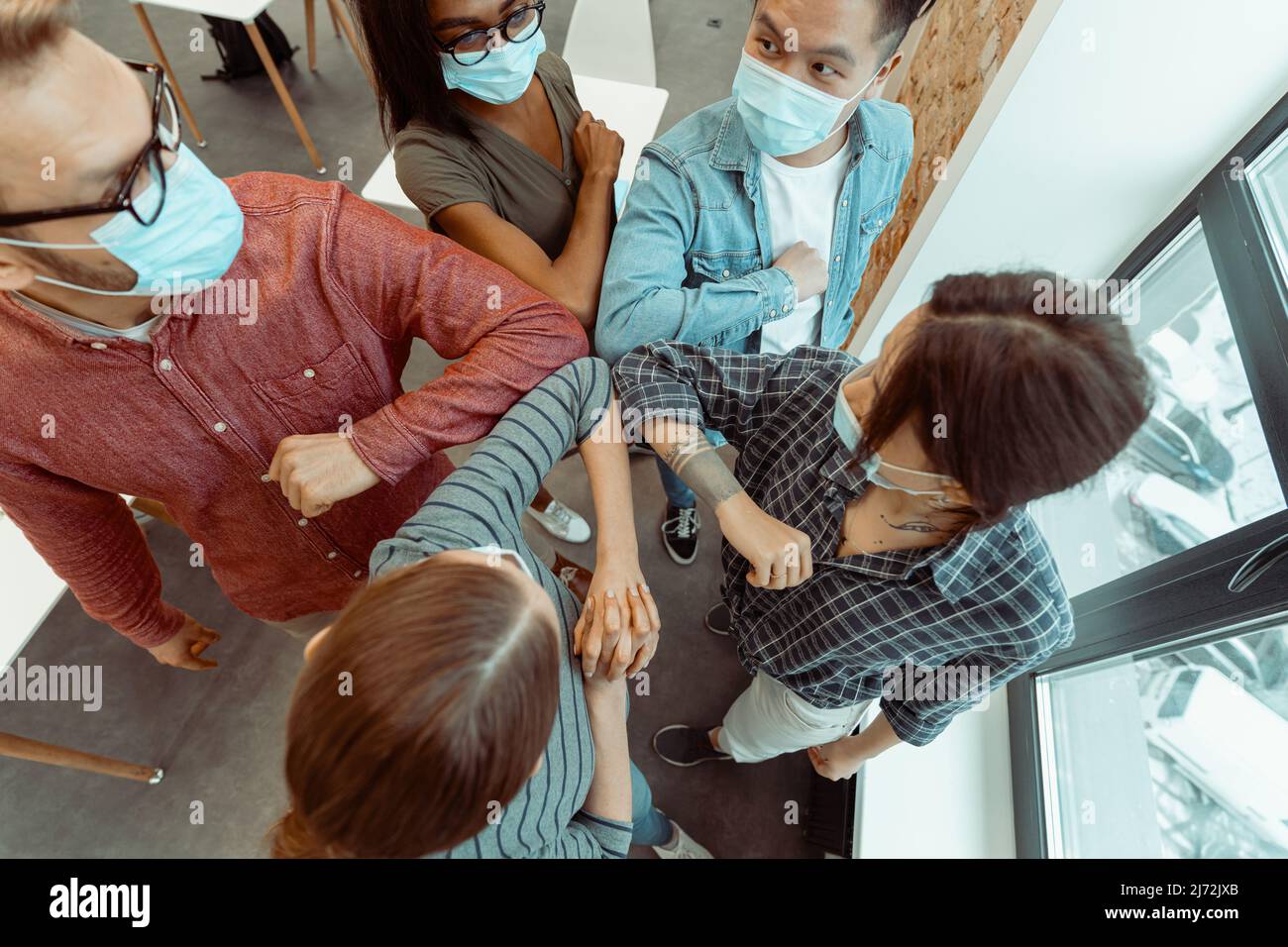 Students greeting each other with their elbows Stock Photo - Alamy