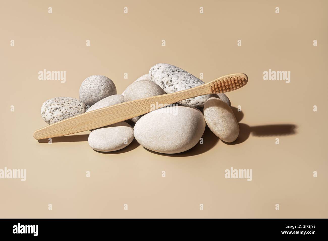 Organic wooden bamboo toothbrush and white sea pebbles on beige ...