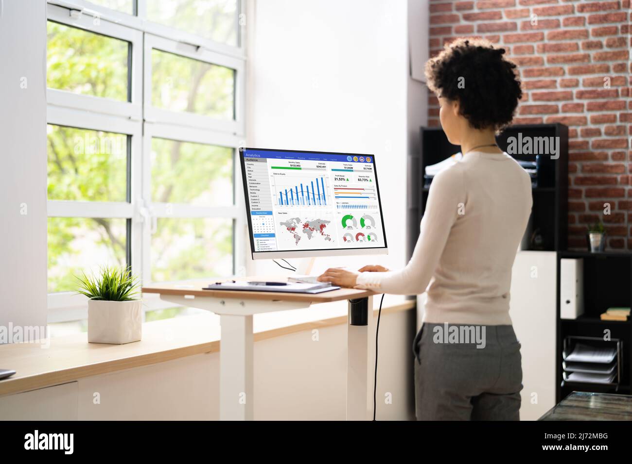 Woman Using Adjustable Height Standing Desk In Office For Good Posture ...