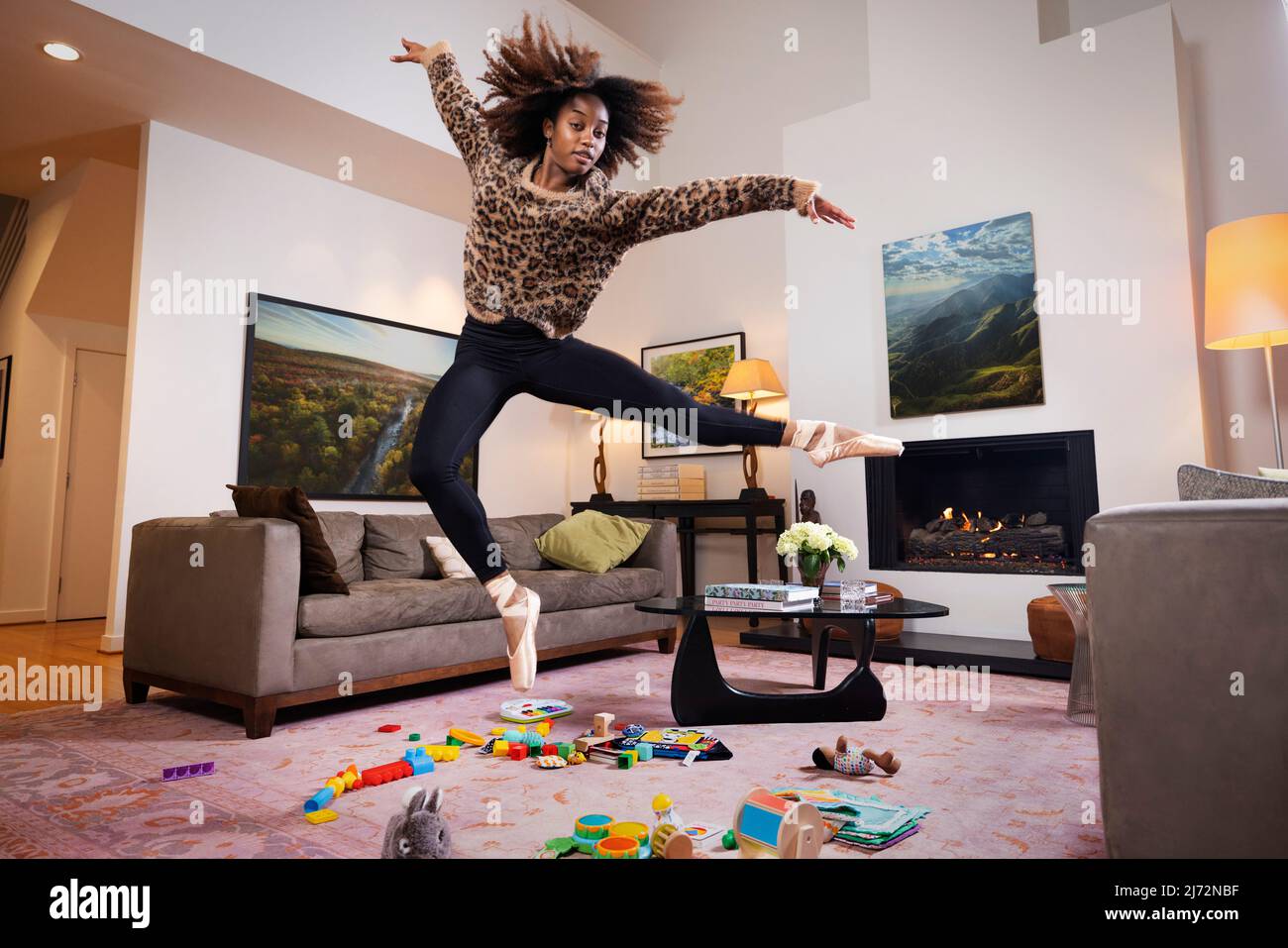 Mother and Ballet dancer jumping over kids toys on floor in living room ...