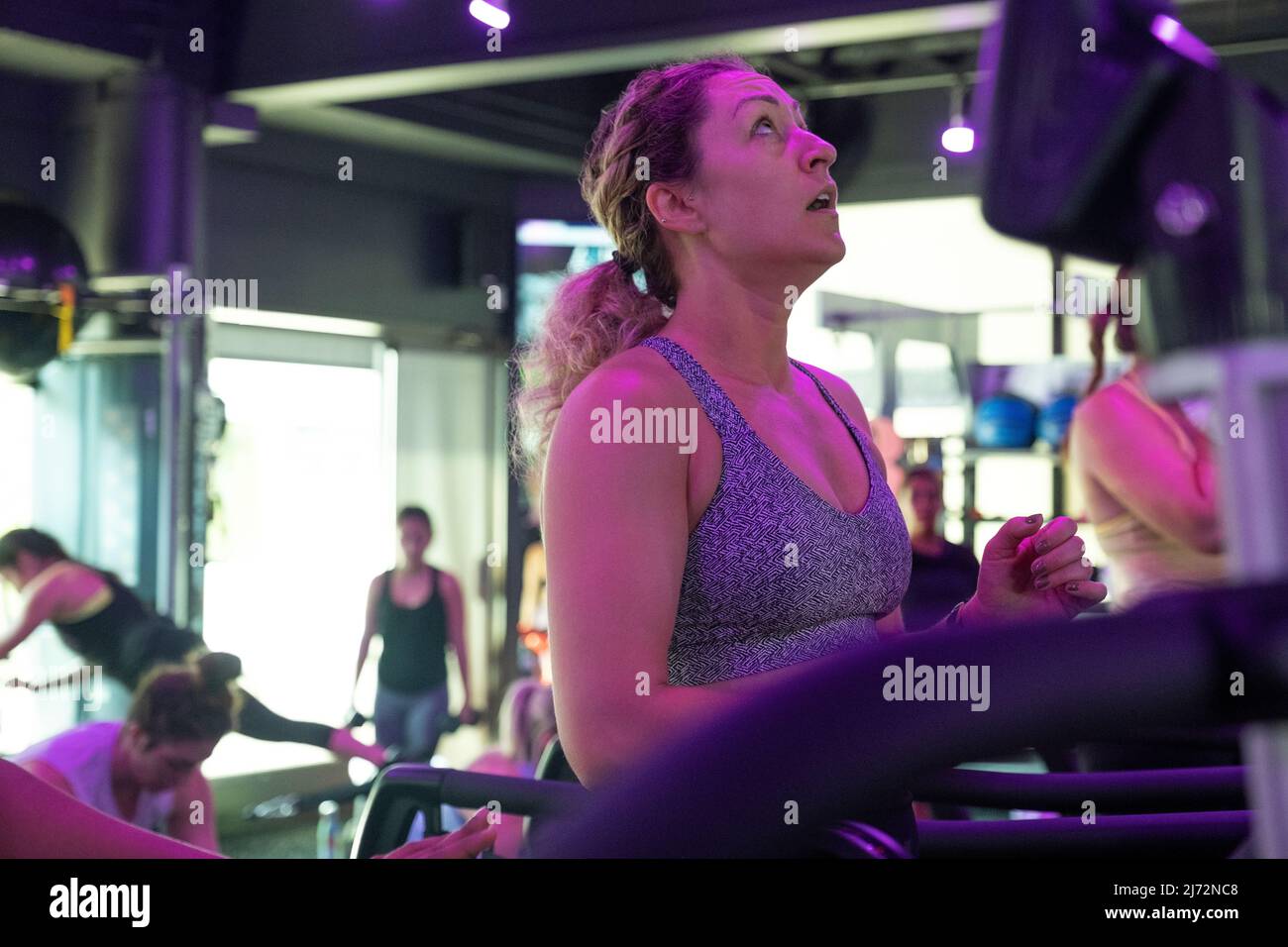 Woman looking up a screen while working out in gym on treadmill Stock ...