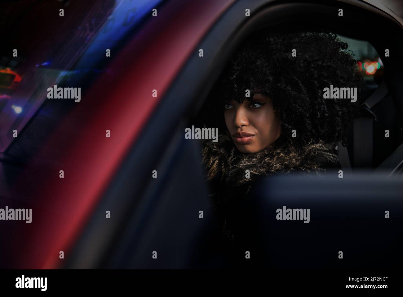 Young African American woman in a sports car looking straight ahead ...