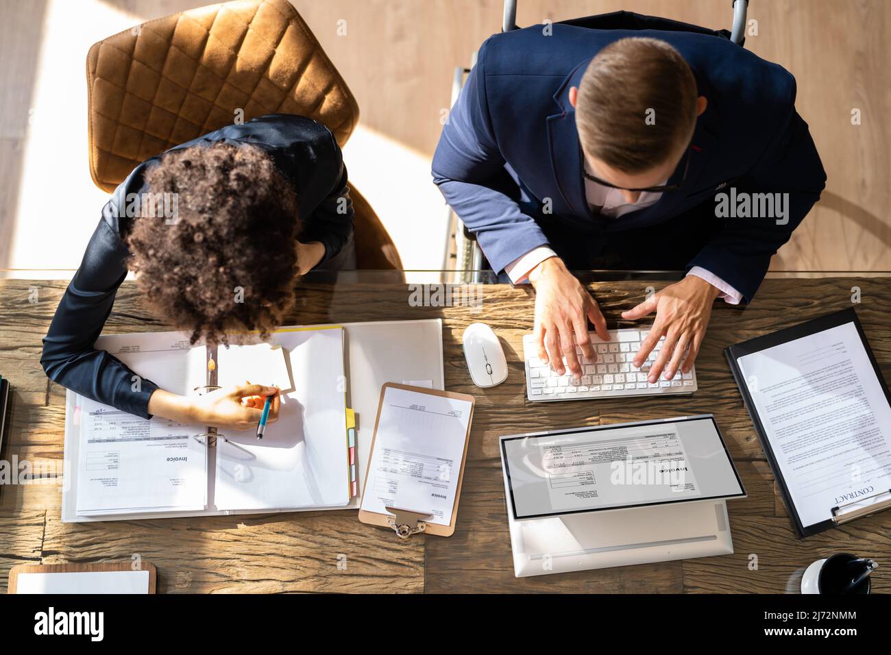 An Overhead View Of Two Businesspeople Calculating Invoice In Office ...