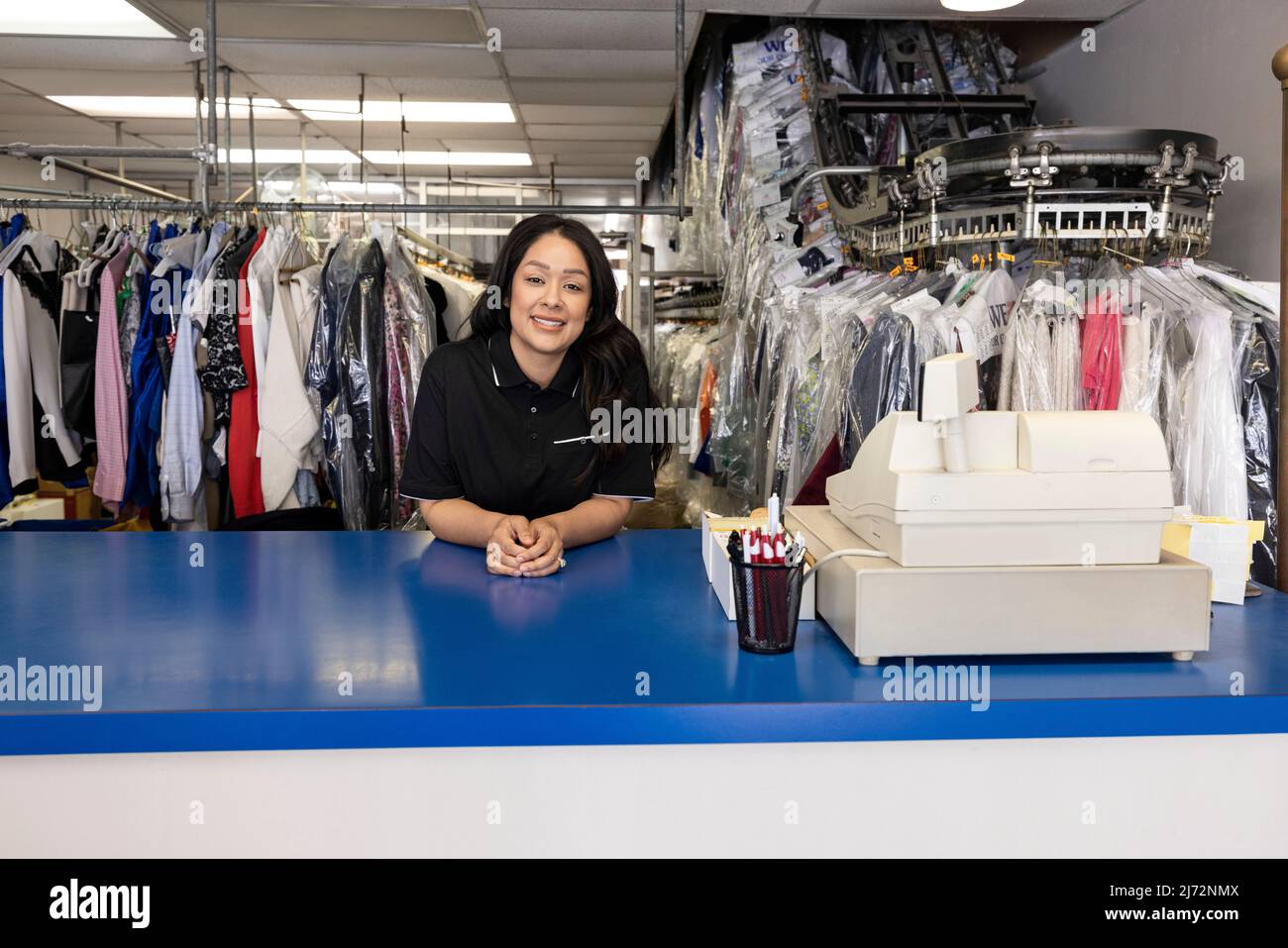 Portrait of young woman at dry cleaning shop Stock Photo - Alamy