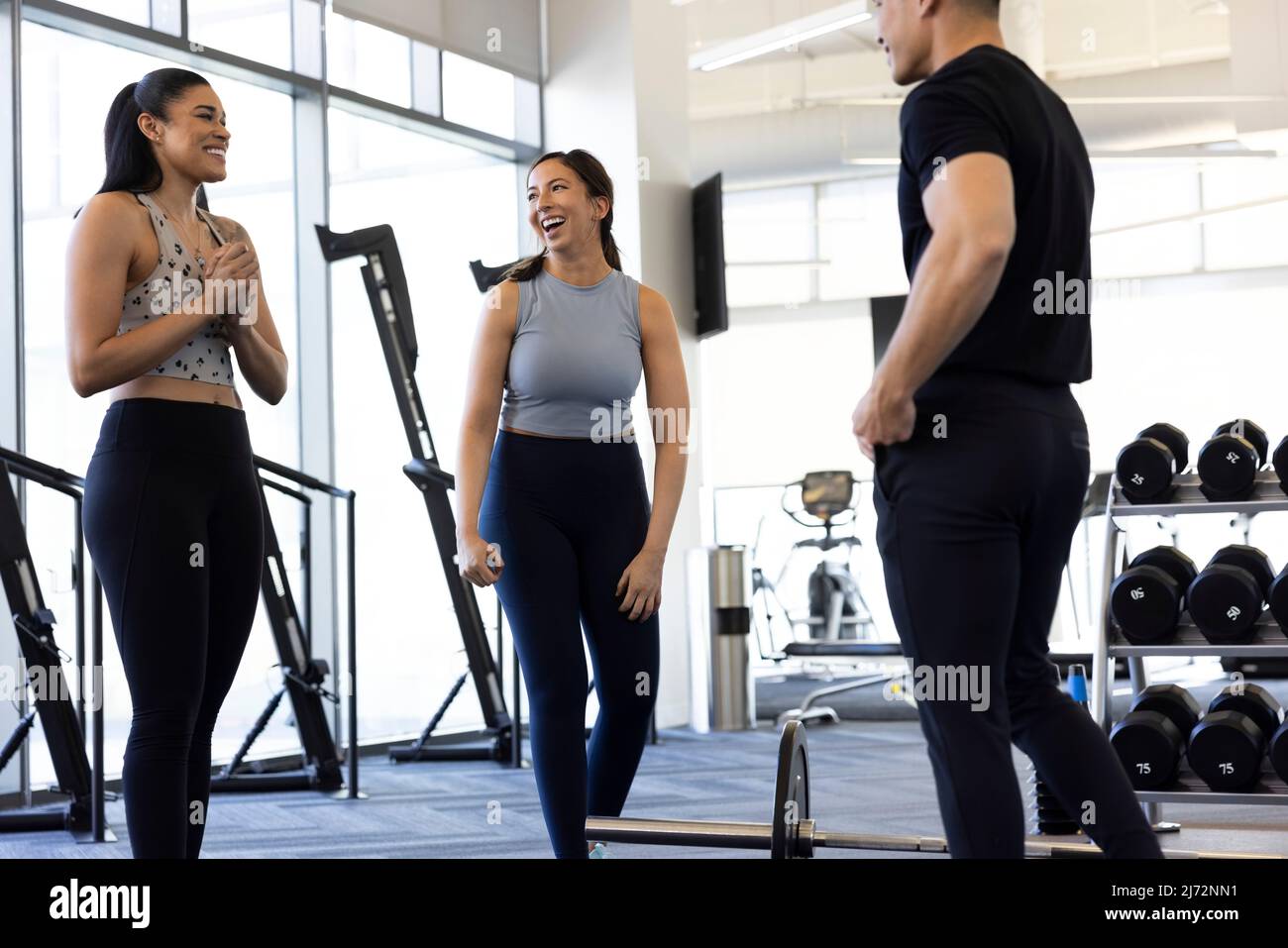 Two woman talking with their trainer after a tough workout in gym Stock ...