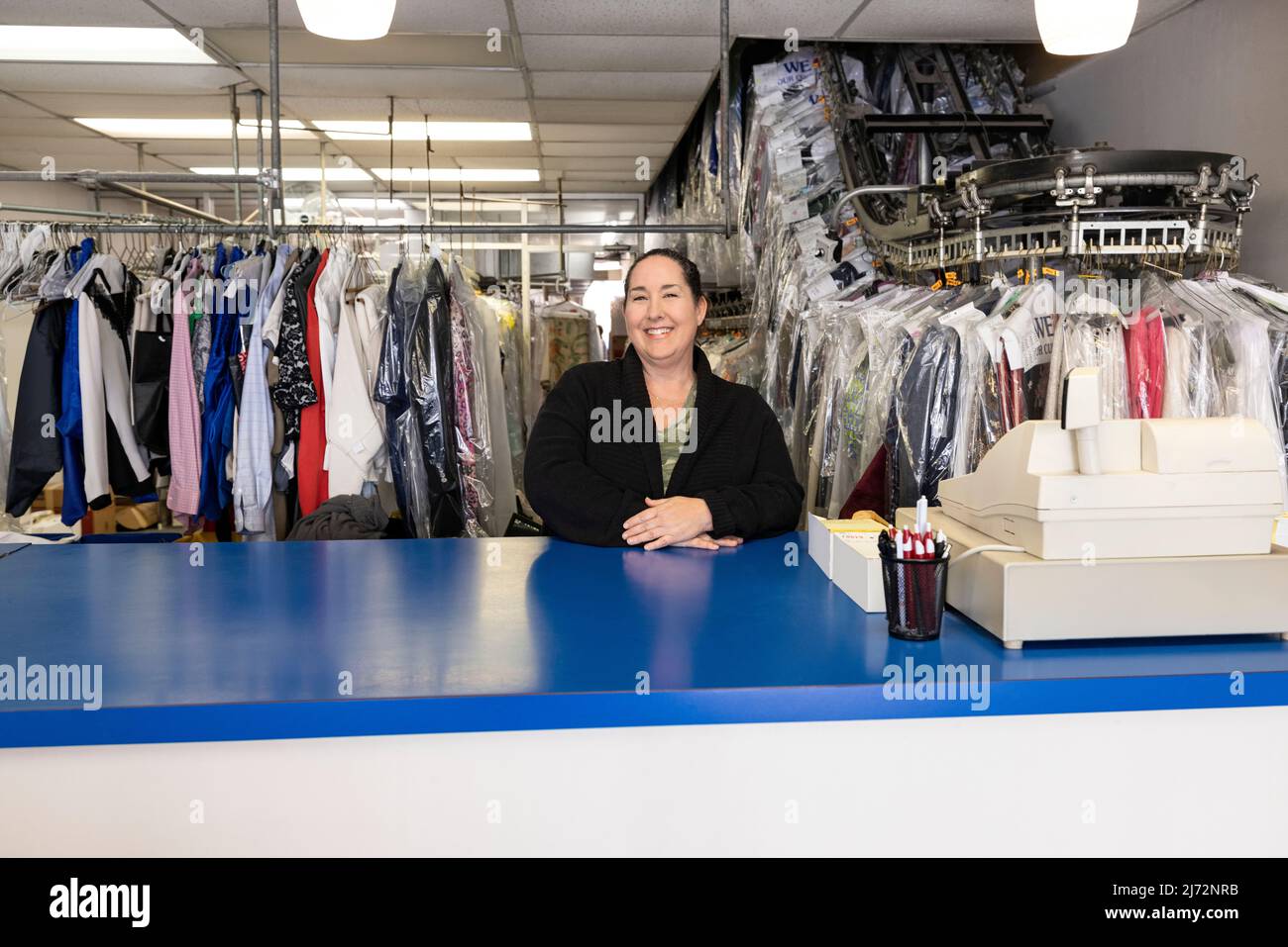 Small business owner of a dry cleaners standing at counter with a ...
