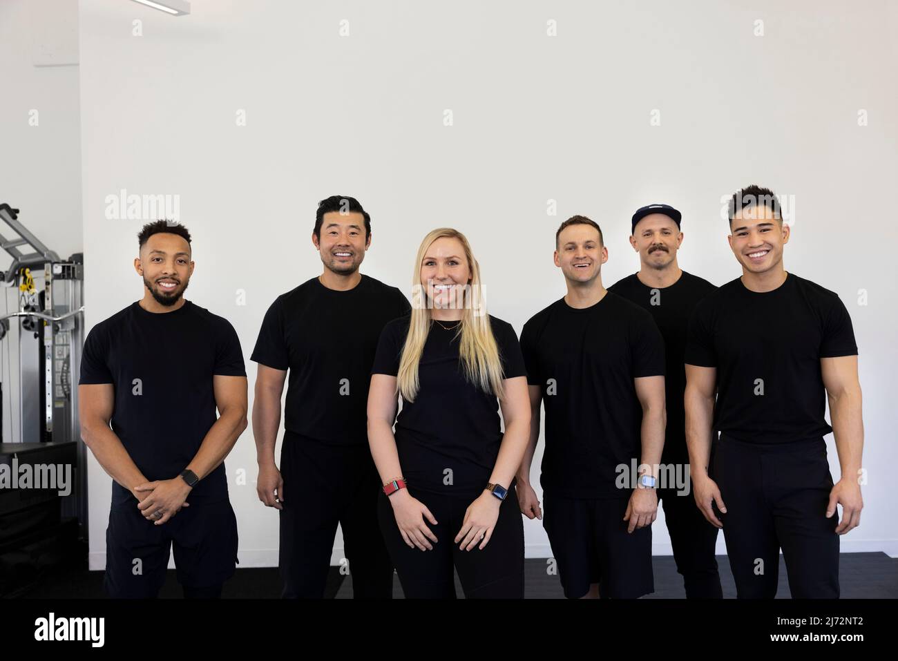 Smiling group of six fitness trainers looking into camera with a ...