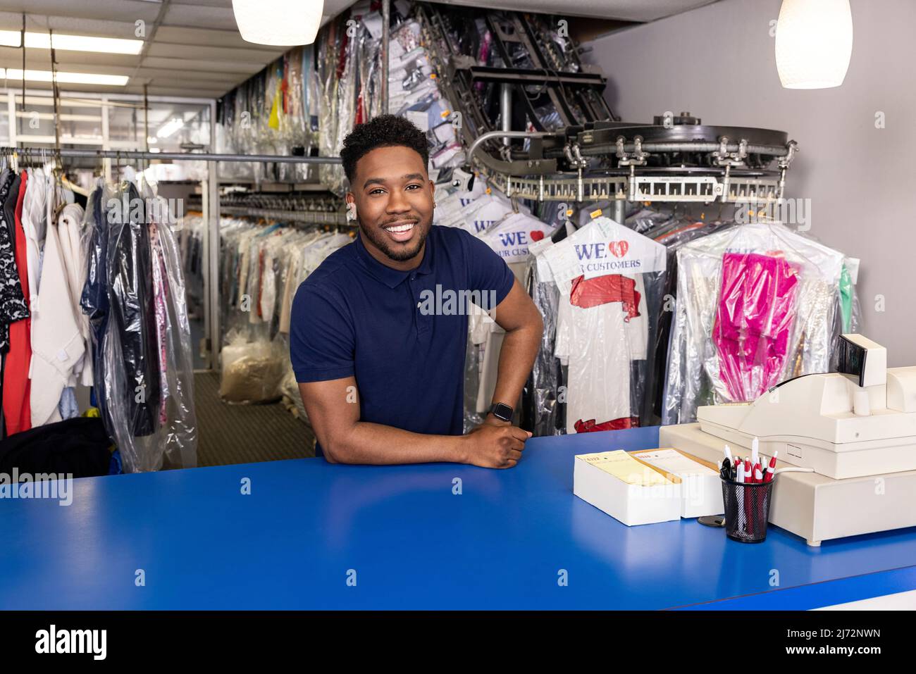 Portrait of small business owner behind counter of dry cleaners looking ...