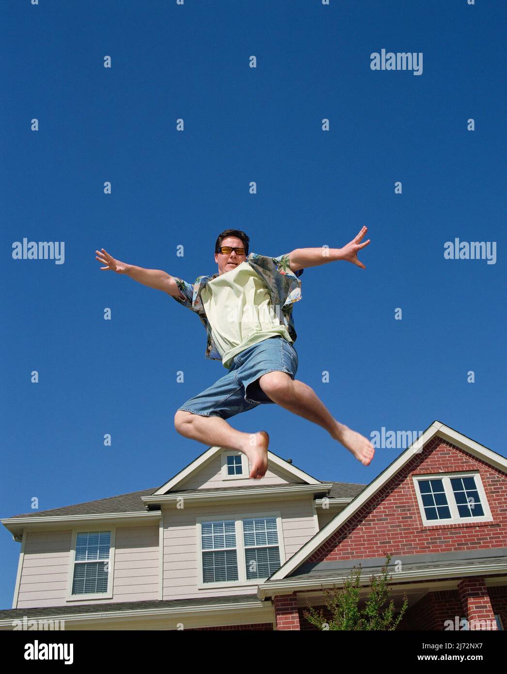 Middle aged man jumping in front of home, striking a pose mid air Stock ...