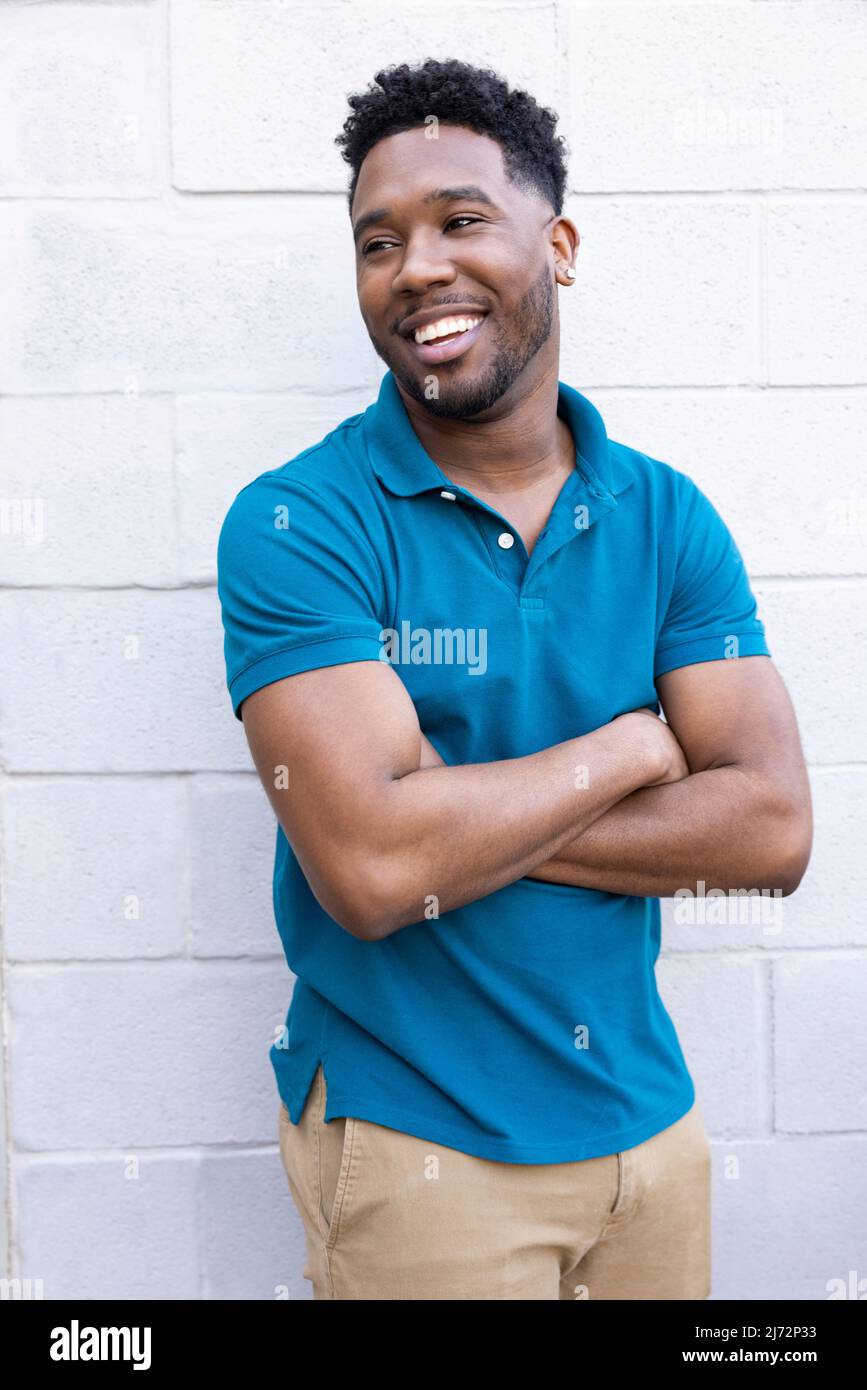 Confident young Black man in blue polo shirt looking off camera smiling ...