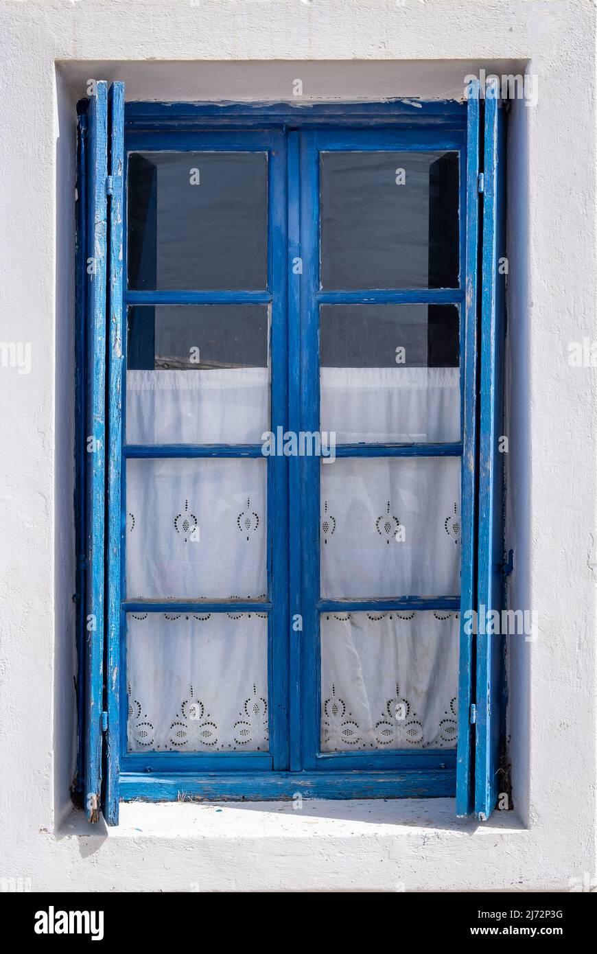 Window with pastel blue open wooden shutters on white wall. Cyclades ...