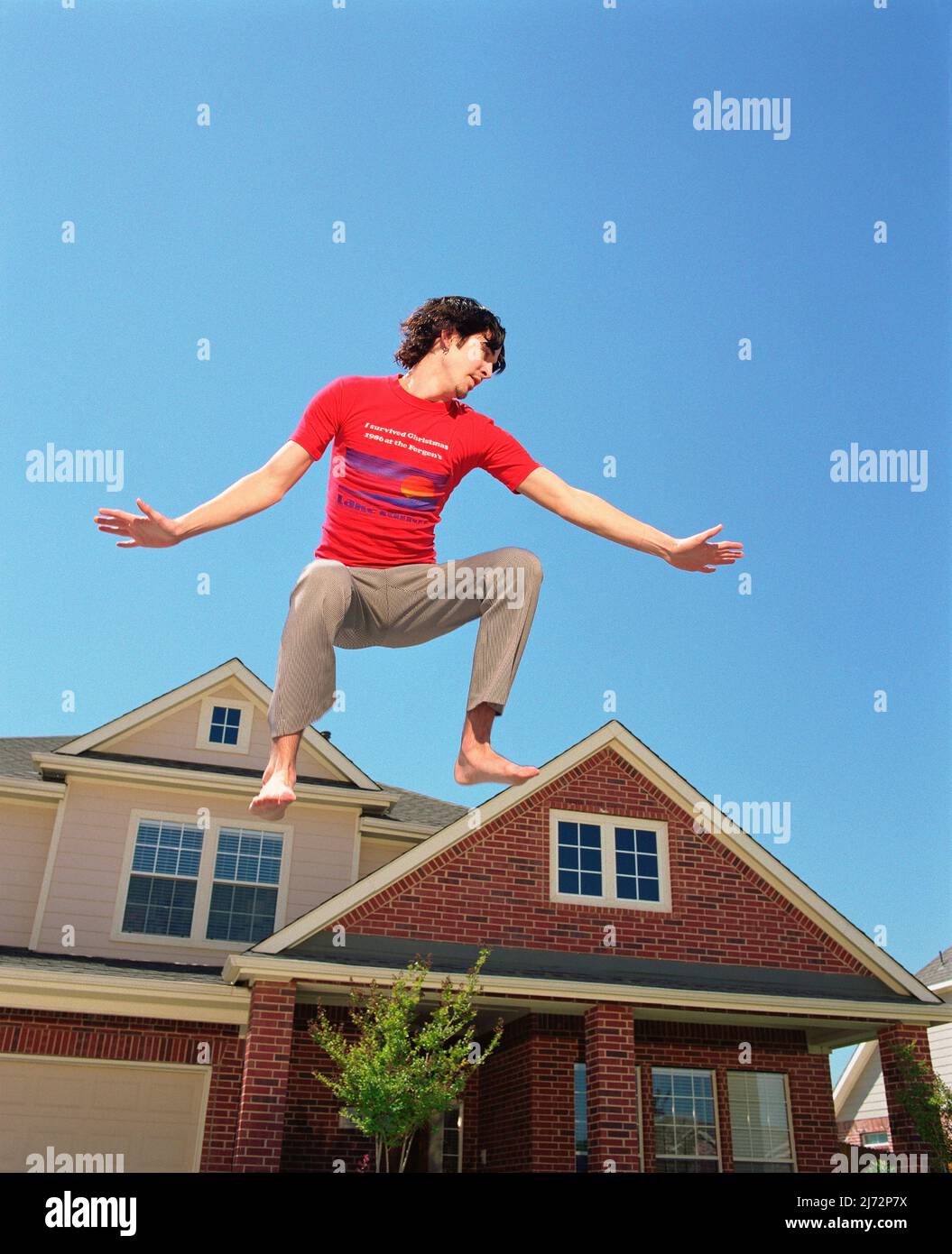 Teenage boy jumping in front of home, striking a pose mid air Stock ...