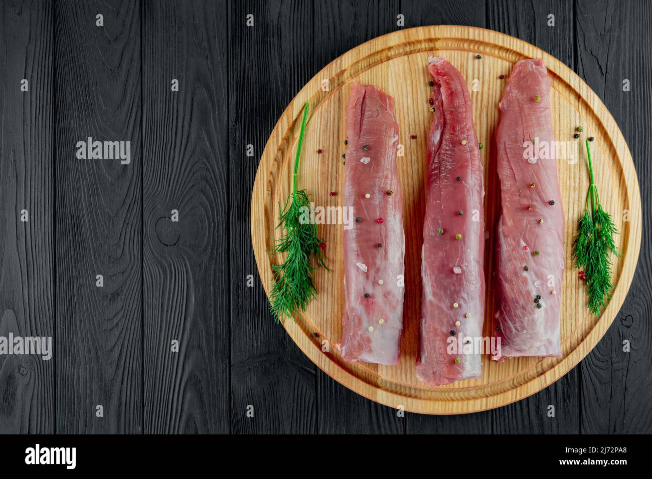 Raw chicken wings lie on a round stand on a black background with ...