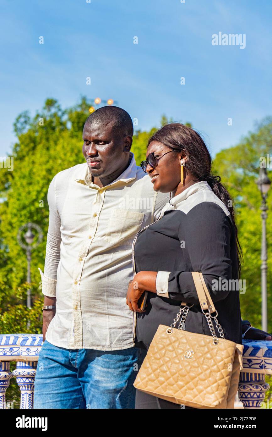 black man and woman couple of tourists consult phone and pose for ...