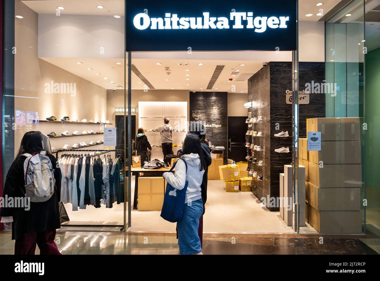 Shoppers walk past the Japanese sports shoe brand Onitsuka Tiger store ...