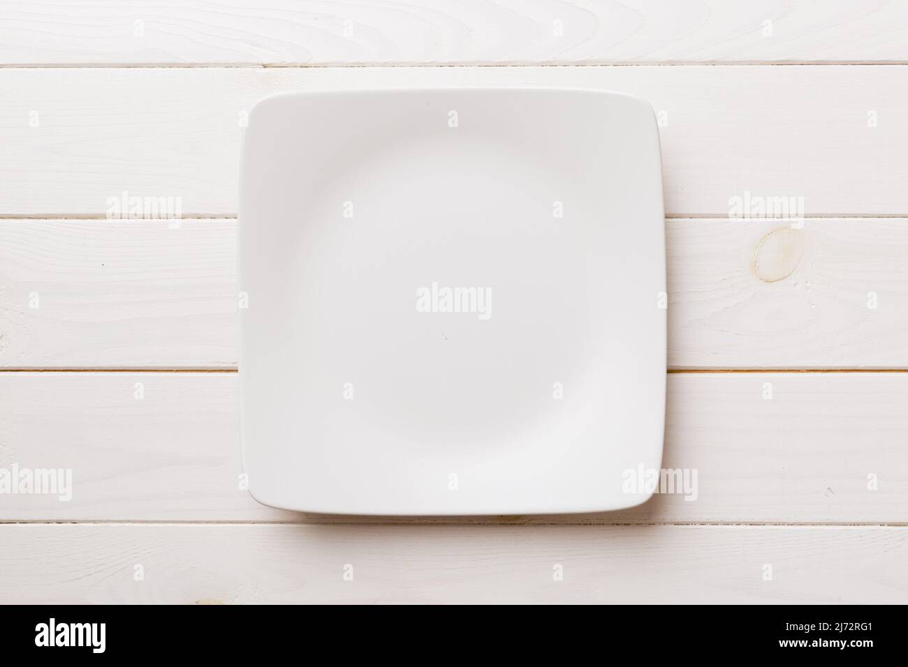 Top view of empty square plate on wooden background. Empty space for ...