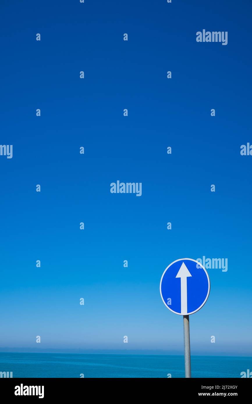 Circle road sign with white arrow on blue sky background. This sign ...